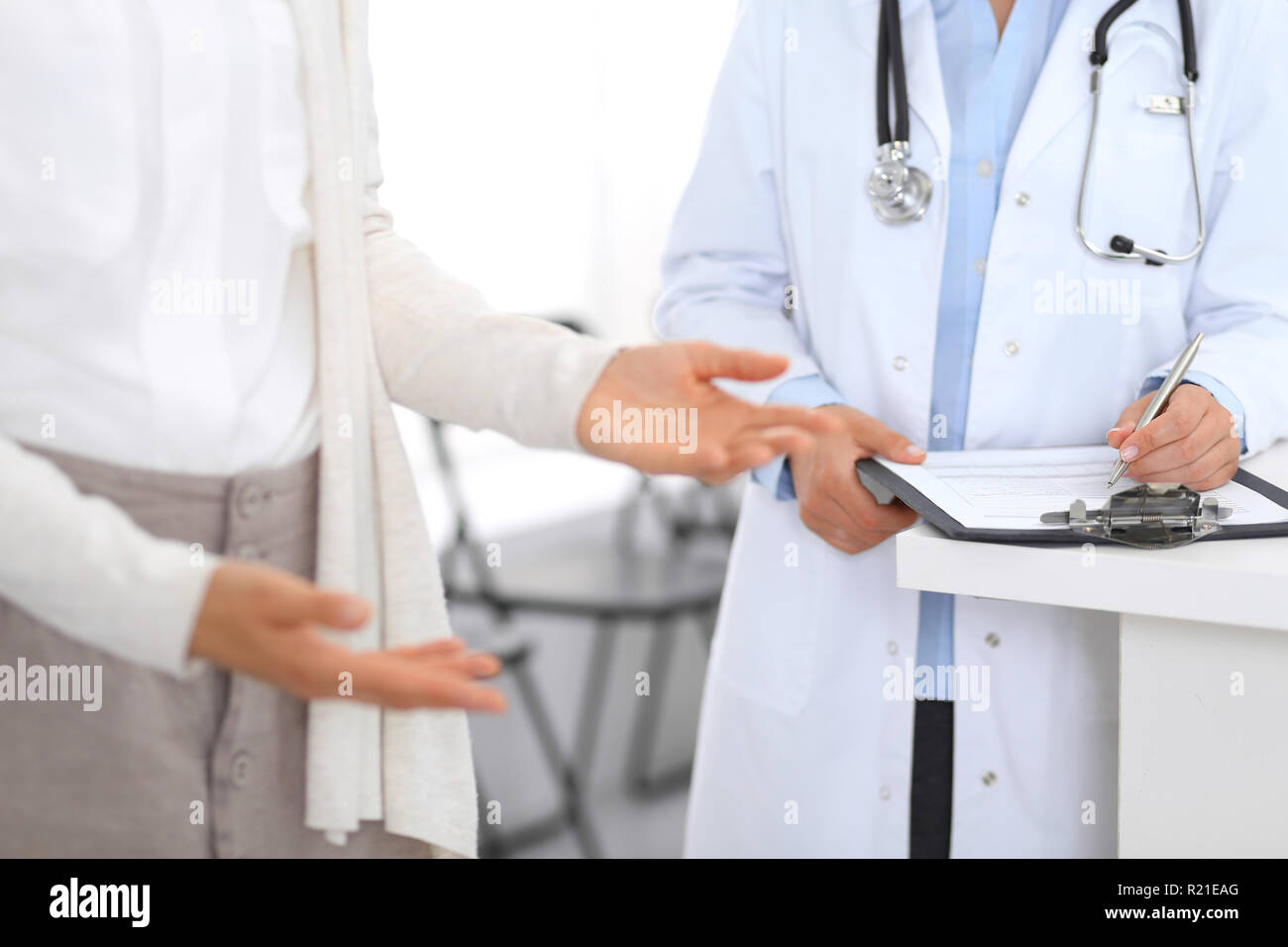 Unknown doctor and female patient discussing something while standing ...