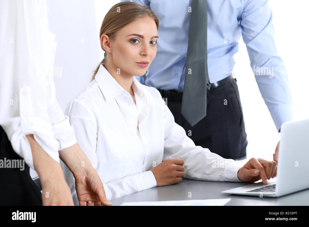 Group of business people using laptop computer while standing in office ...