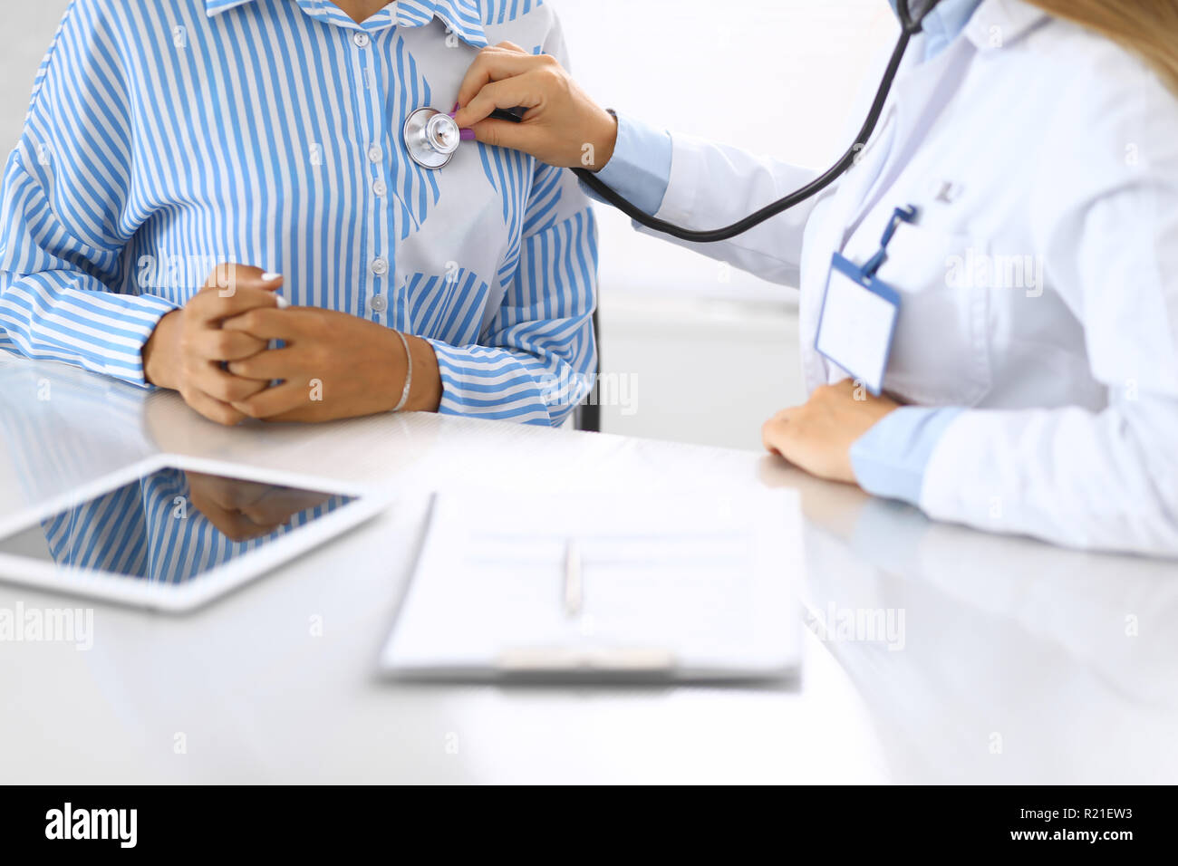 Doctor with a stethoscope in the hand. Physician examines her female ...