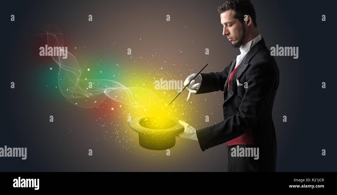 Illusionist hand starts to conjure with white glove and magic wand ...