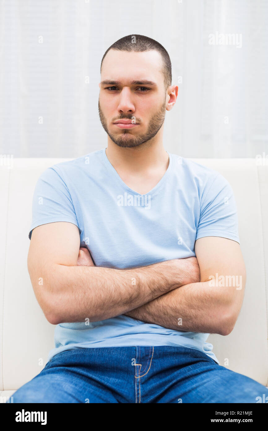 Angry young man sitting at sofa Stock Photo - Alamy