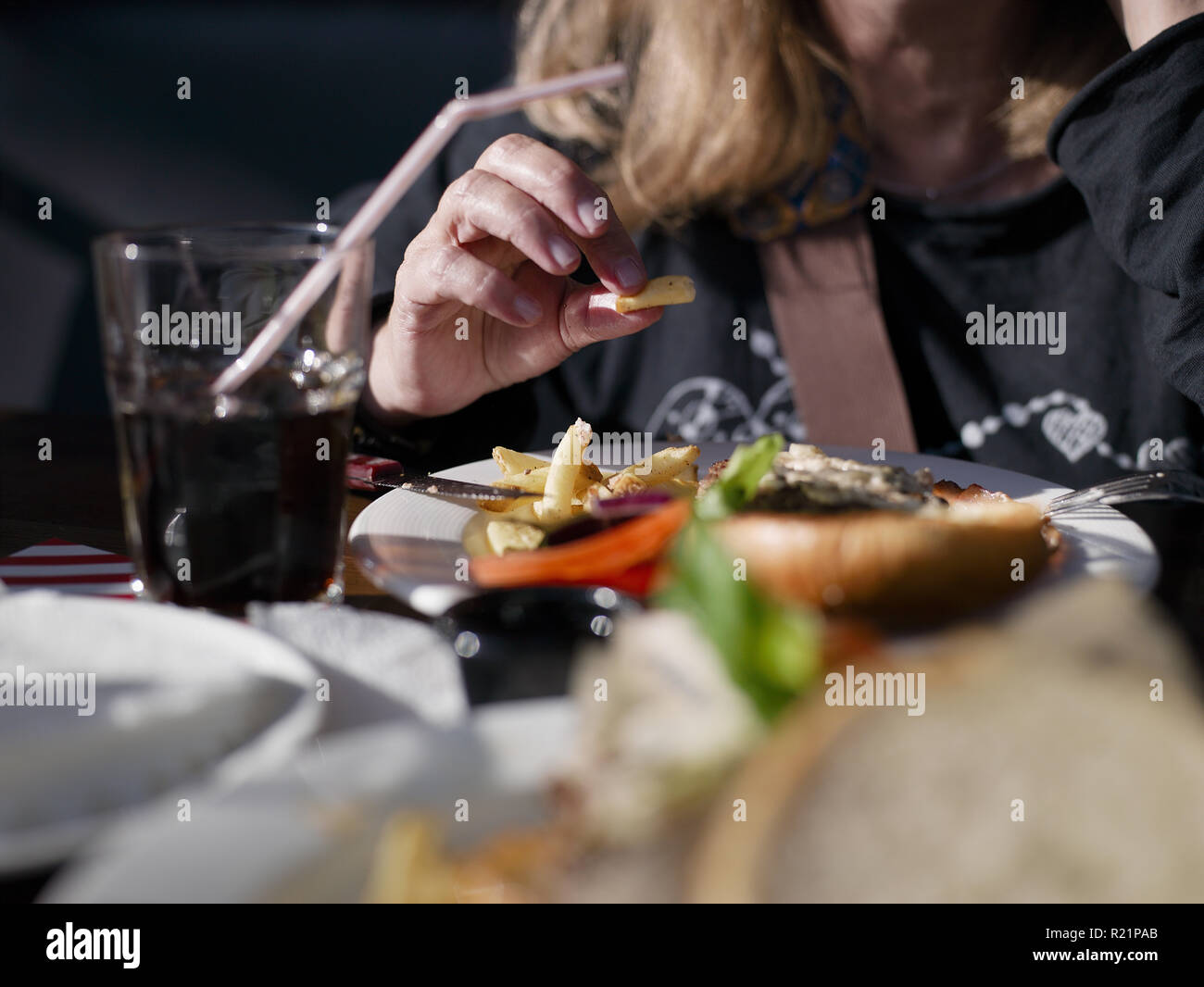 Shallow depth of field shot of a woman eating at the messy table with ...