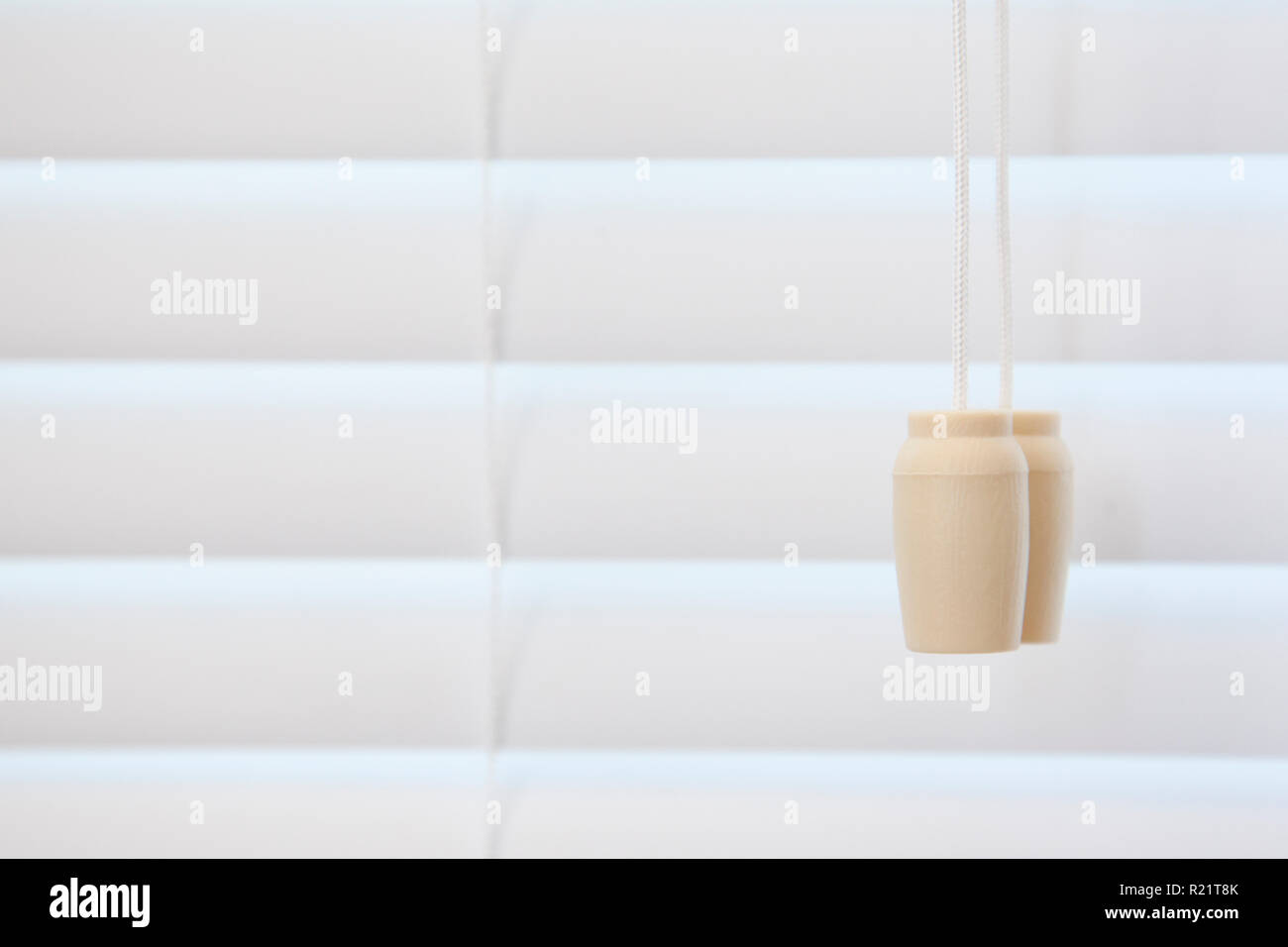 A string for pulling a blind open and closed beside a drawn shutter ...