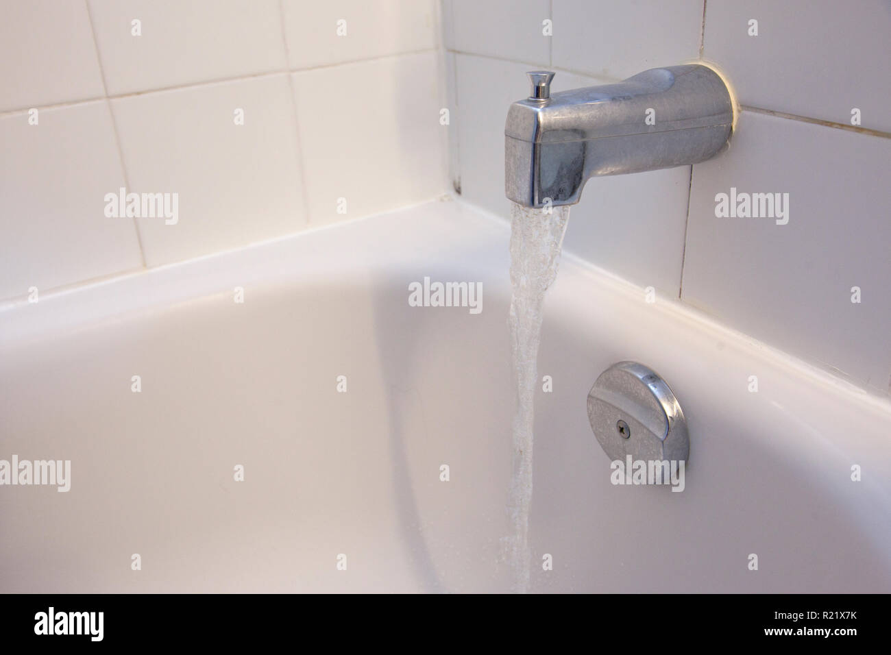 A bathroom shower stall with the tub faucet running water and copy ...