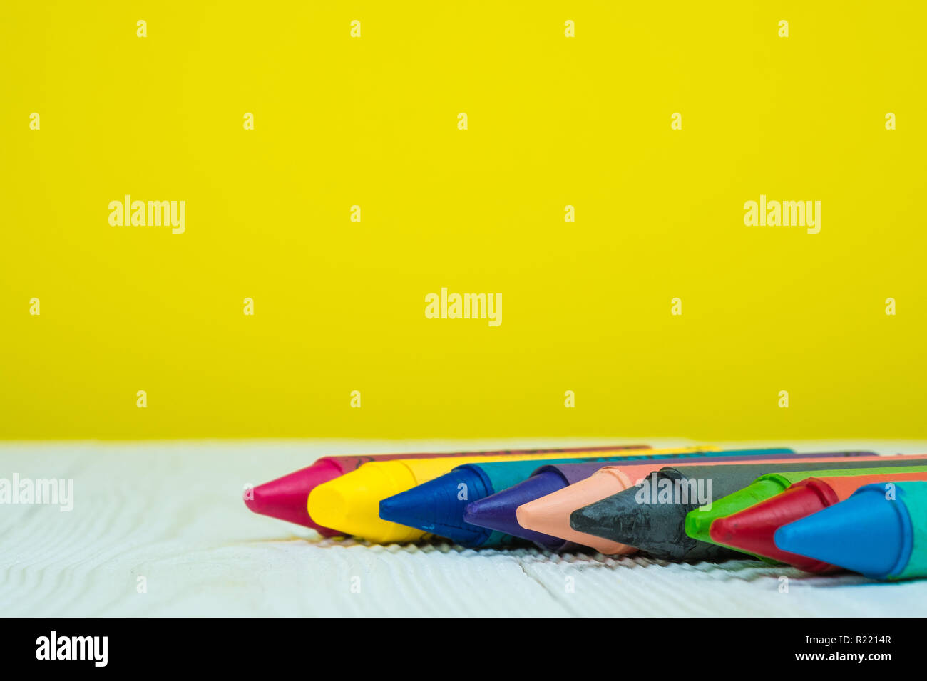 Colourful wax crayons pencils on white wood table with copy space for ...