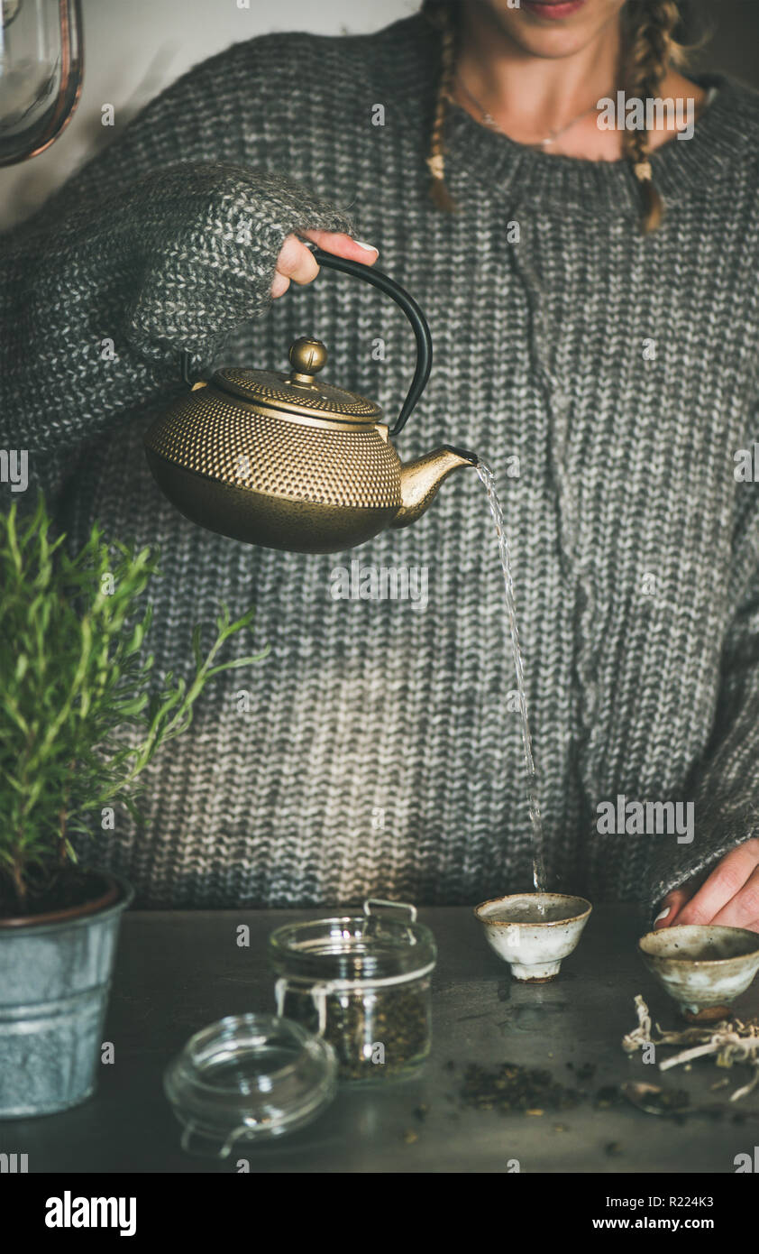 Female in sweater pouring green tea from pot Stock Photo - Alamy