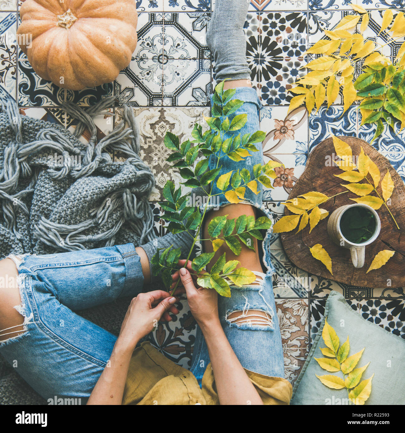 Female sitting on balcony holding fallen autumn leaves, square crop ...