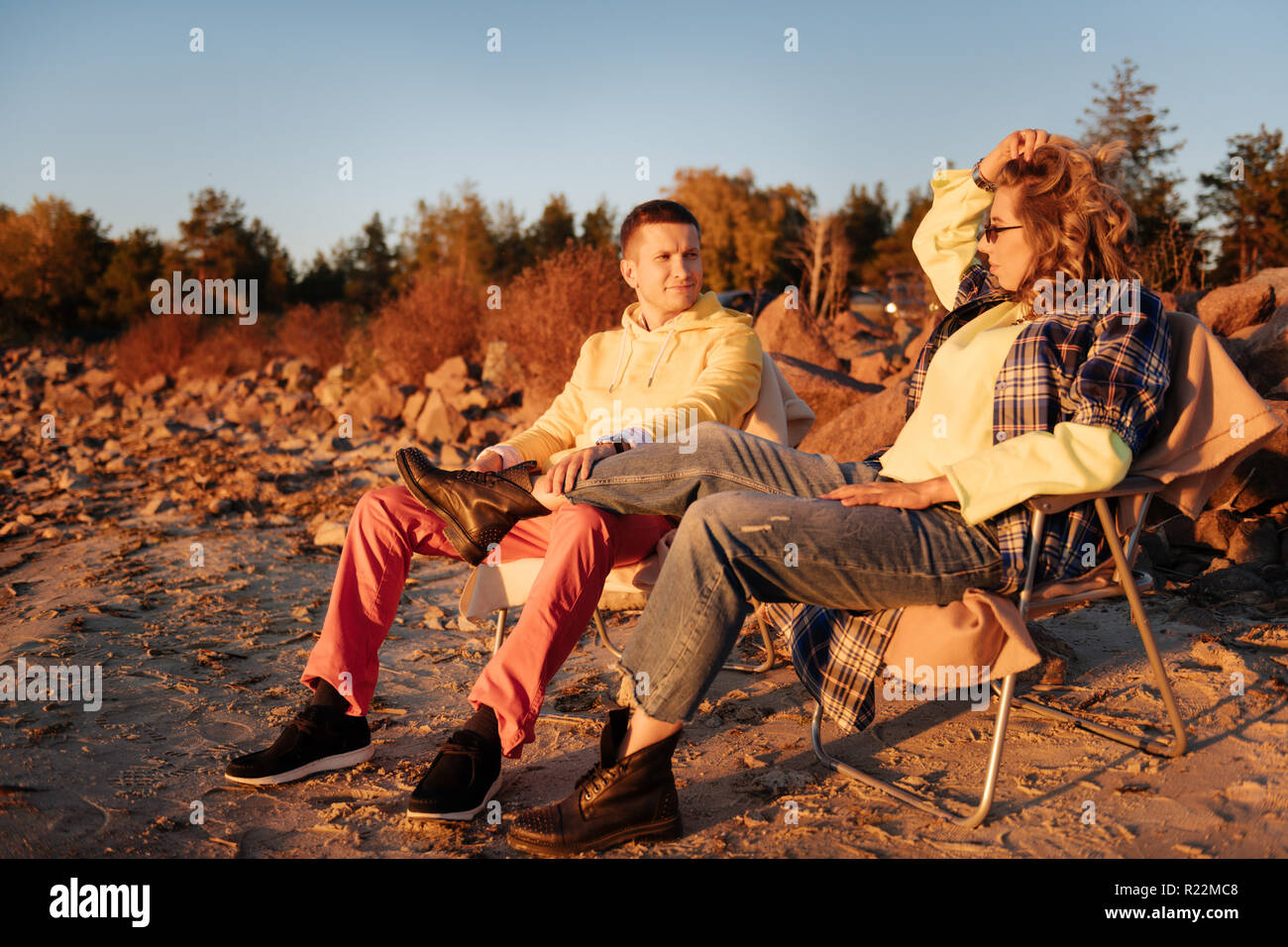 Young family sitting on the folding armchairs at the sunset Stock Photo ...