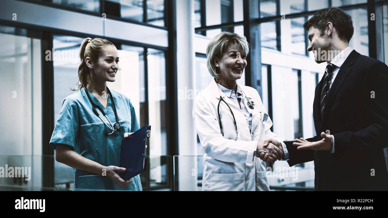 Female doctor shaking hands with businessman Stock Photo - Alamy