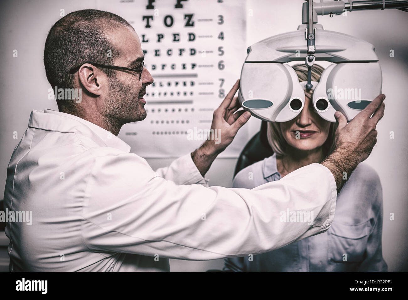 Smiling optometrist examining female patient on phoropter Stock Photo ...
