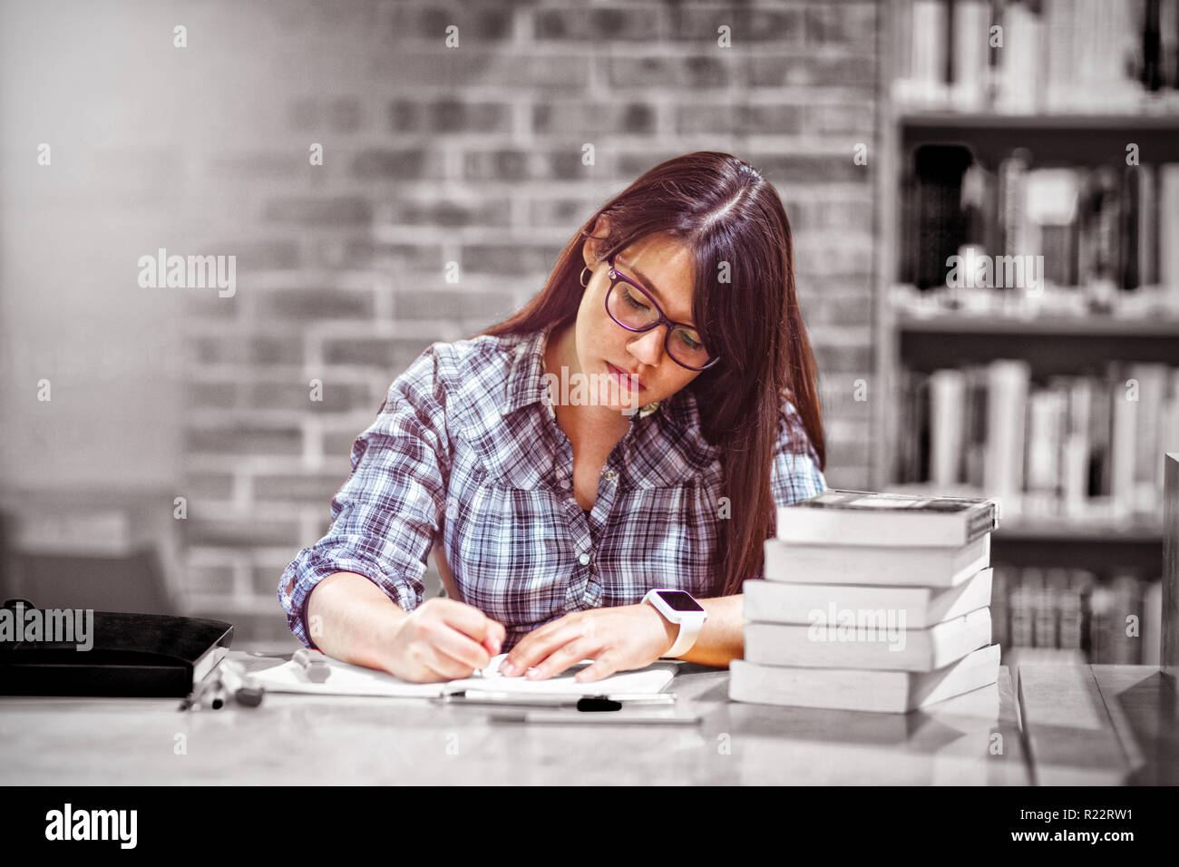 Female student writing notes in library Stock Photo - Alamy