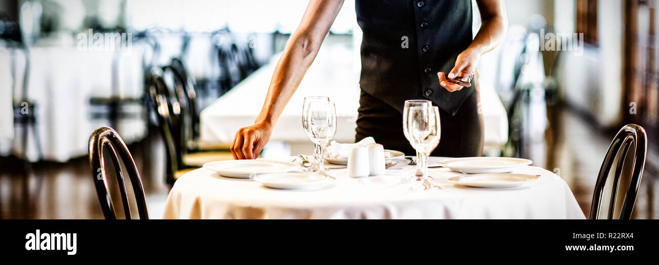 Smiling waitress setting the table Stock Photo - Alamy