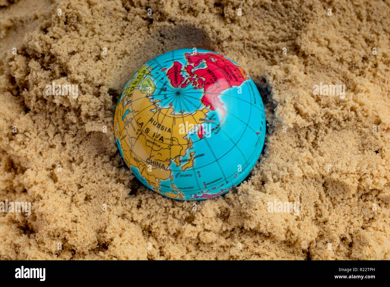 Little model globe on sand in view Stock Photo - Alamy