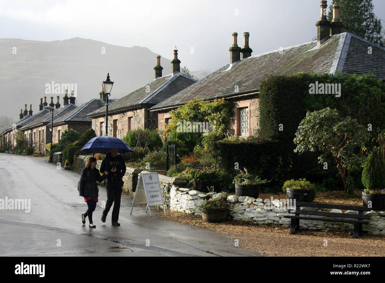 A couple walks under an umbrella in the rain in Luss, Scotland Stock ...