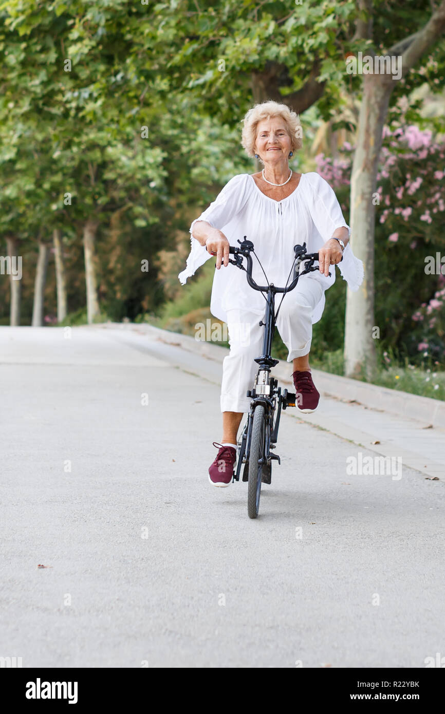 Smiling senior lady riding modern bike in summer nature Stock Photo - Alamy
