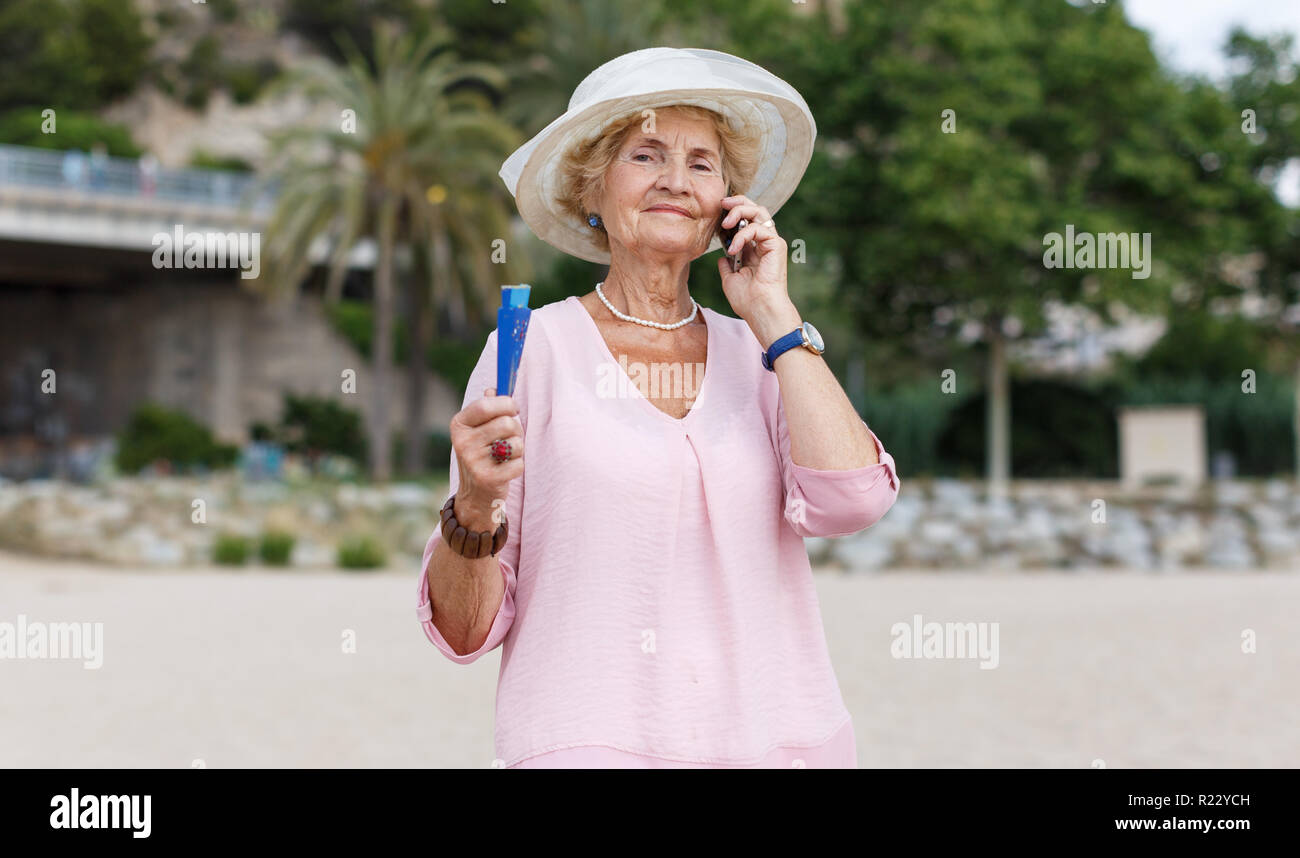 Portrait of senior lady making phone call while resting at beach Stock ...