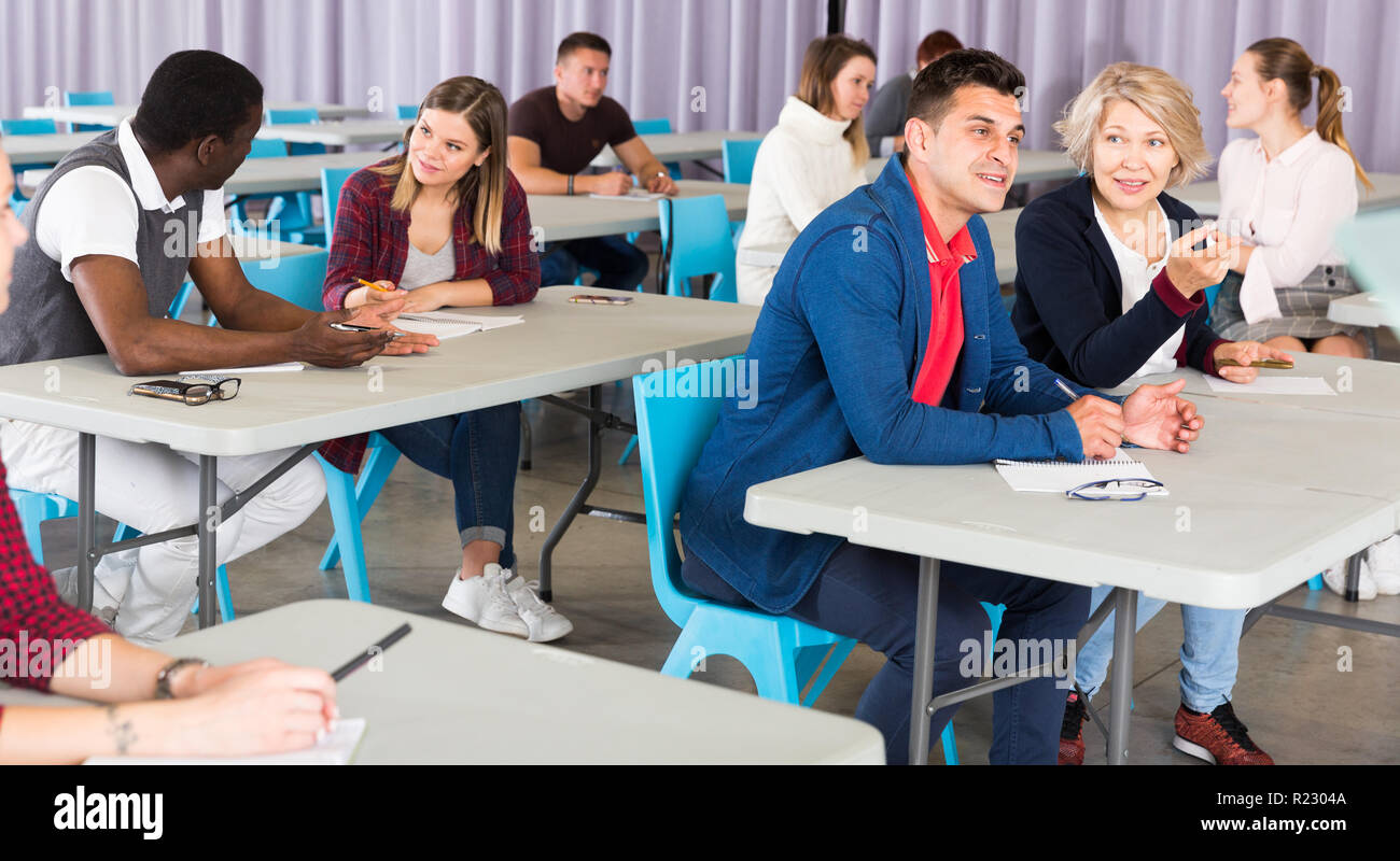 Group of adult education students studying together in class ...