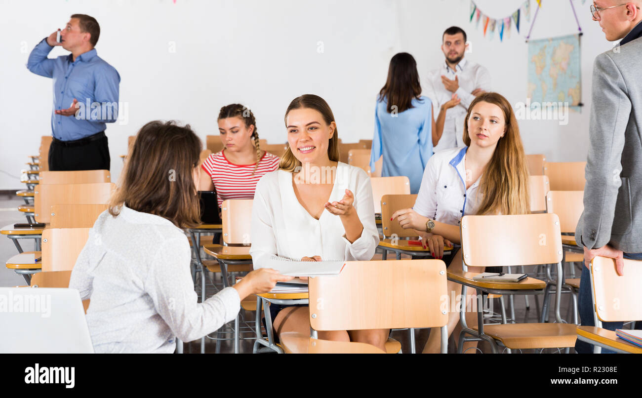 Happy group of adult students lively chatting while enjoying free time ...