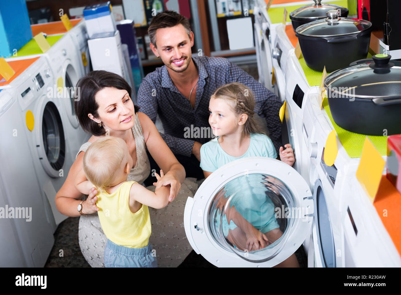cheerful russian parents with two kids choosing washing machine in home ...