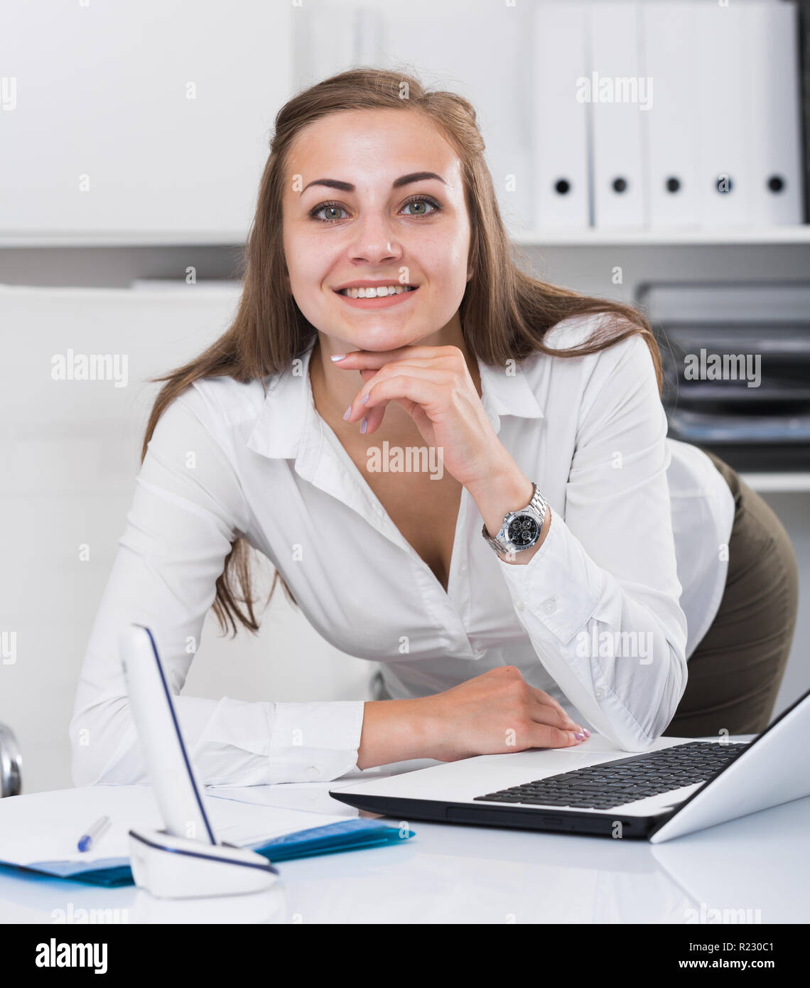 Woman employee is posing while working behind laptop in the office ...