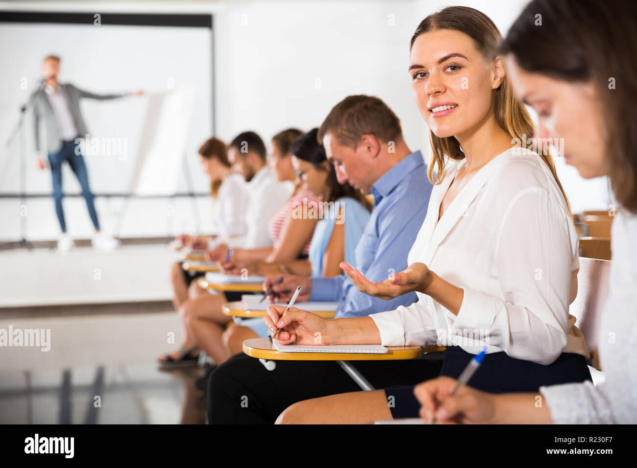 Side view of intelligent girl sitting with her fellow students in ...
