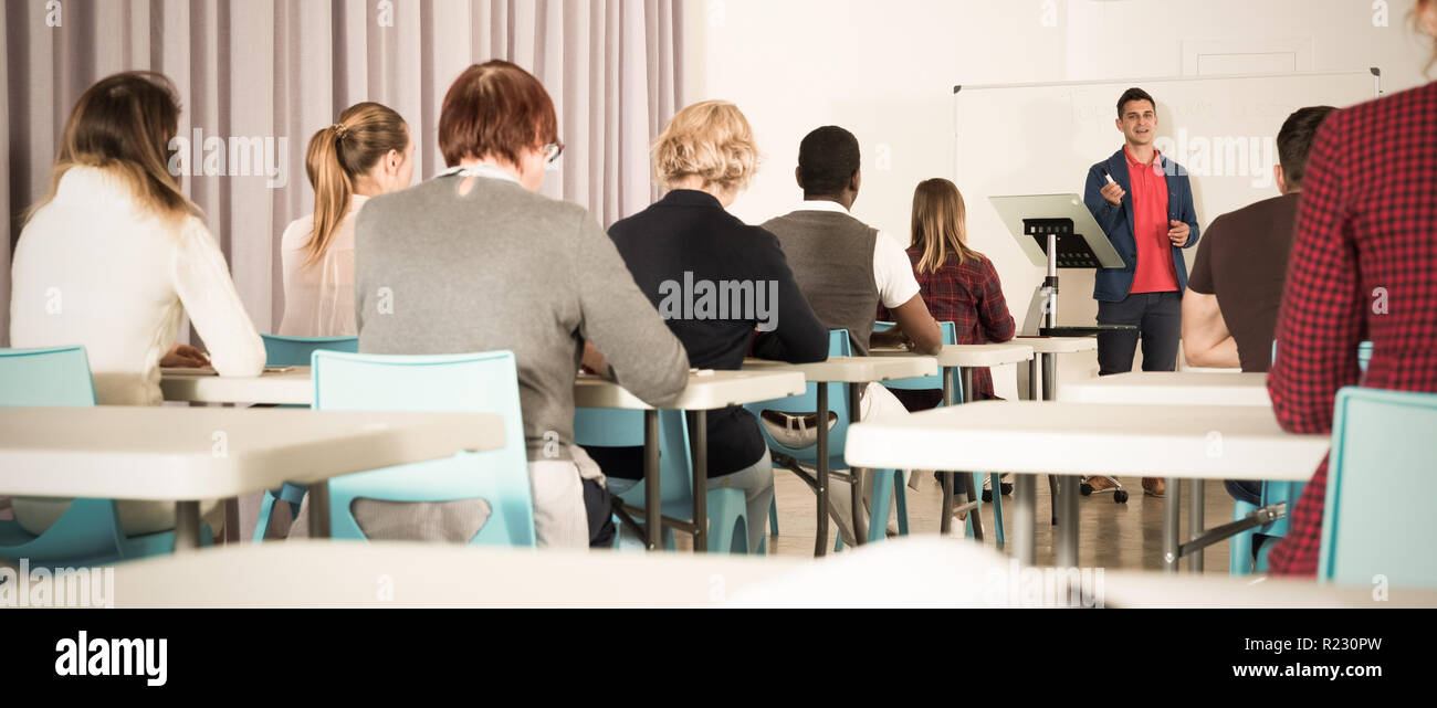 Students of different age sitting together at tables, doing group study ...