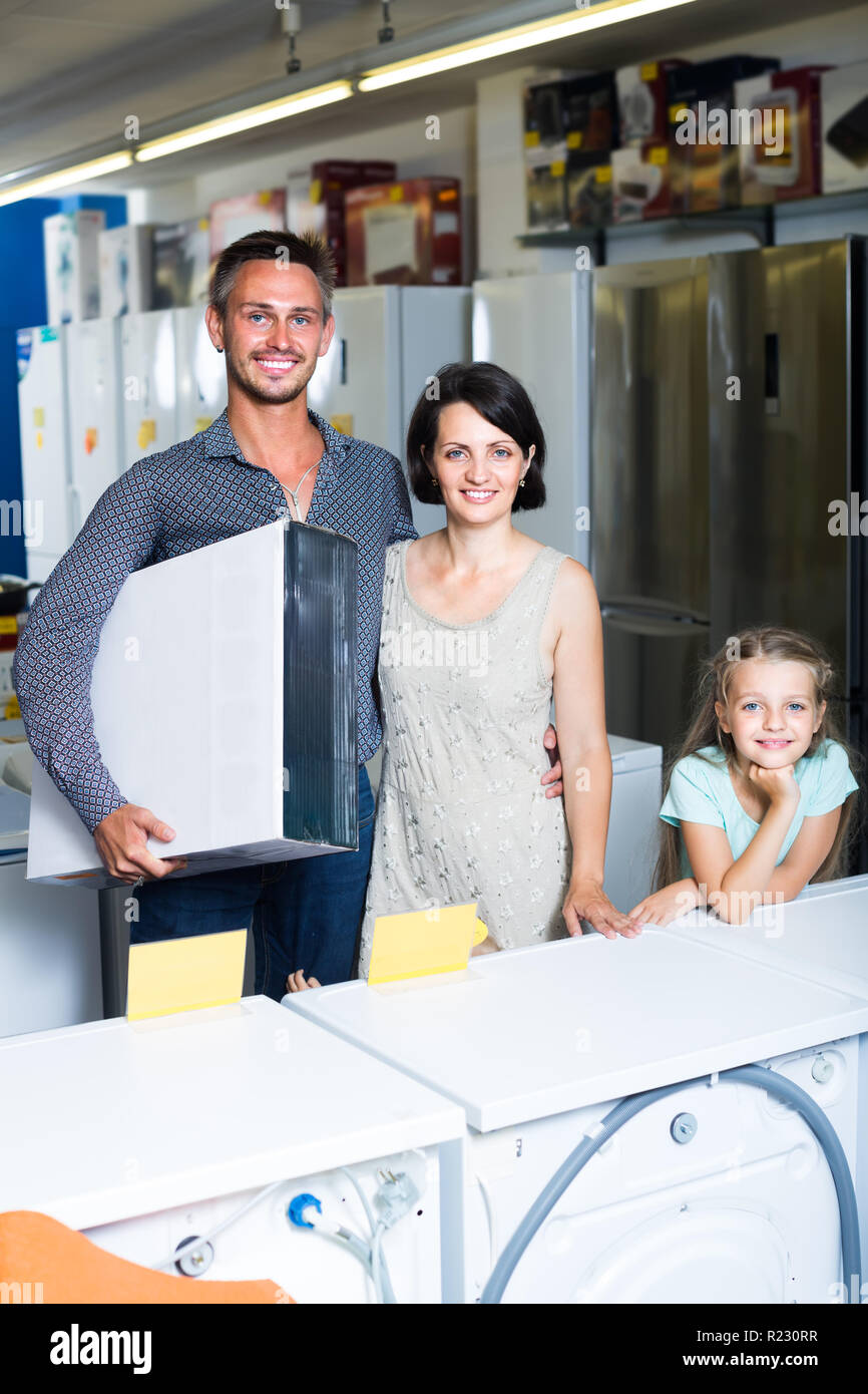 cheerful smiling family of three having new electronics in box in home ...
