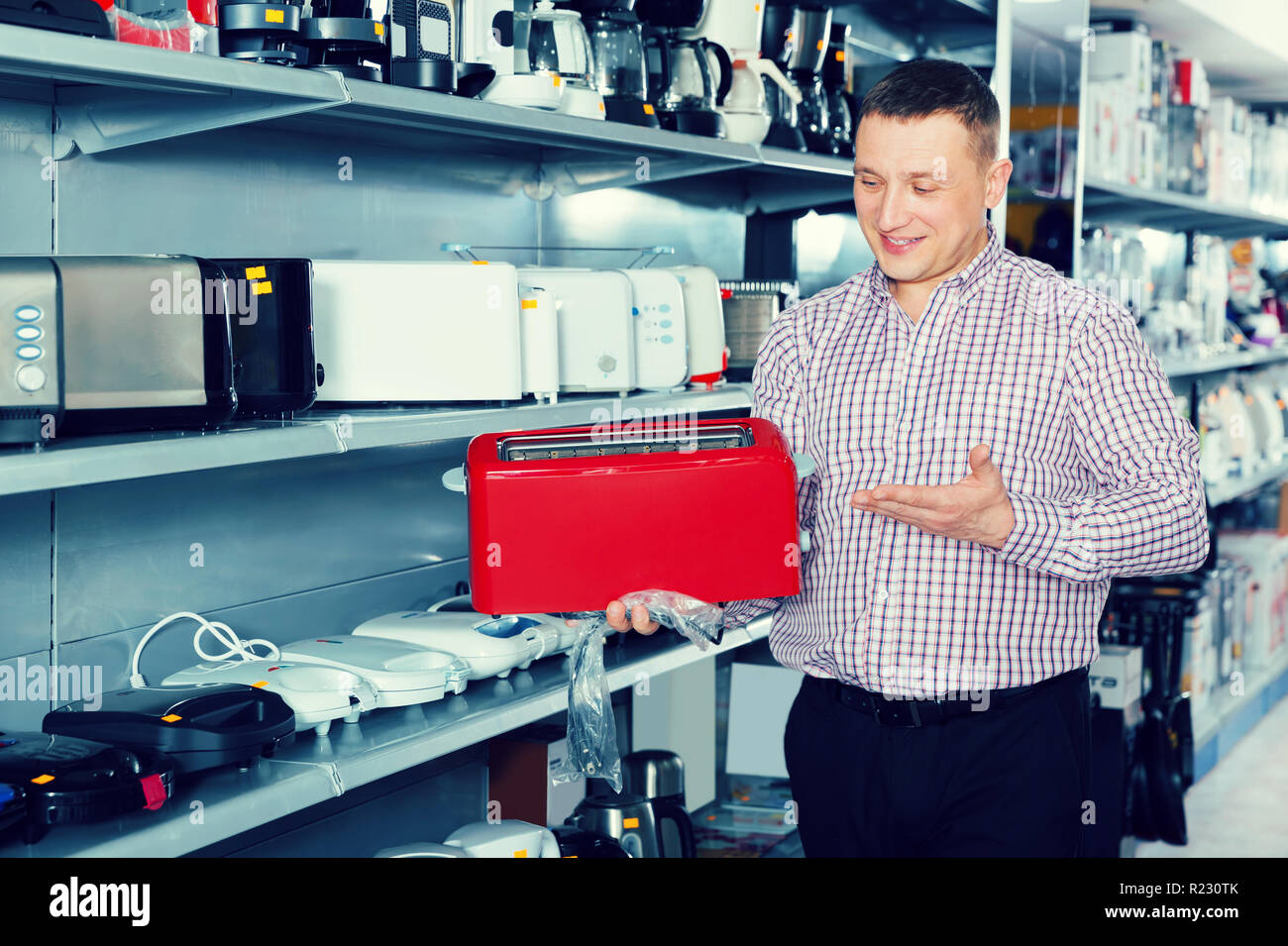 Young man demonstrating new modern toaster in furniture store Stock ...