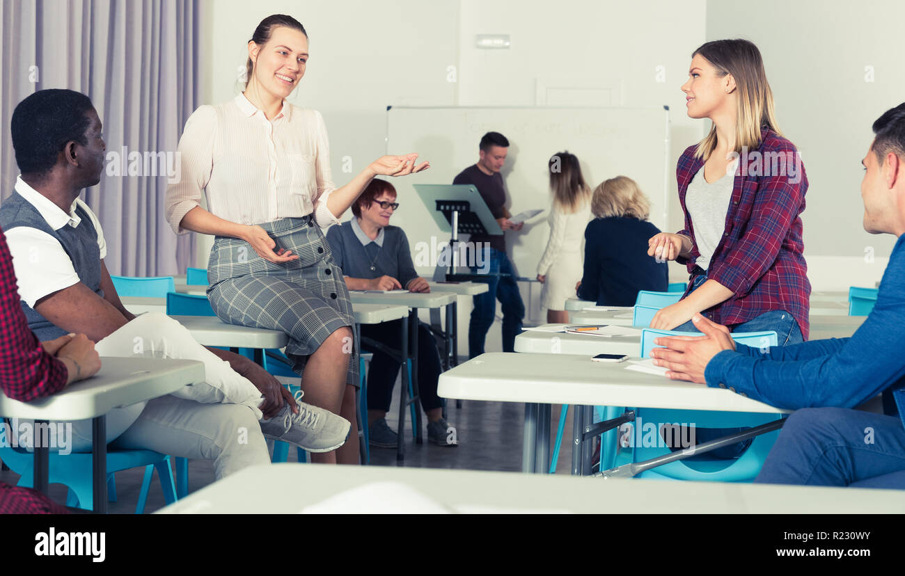 Friendly multinational group of students talking in classroom having ...