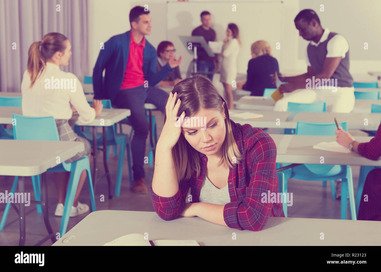Portrait of frustrated young woman student sitting separately in ...