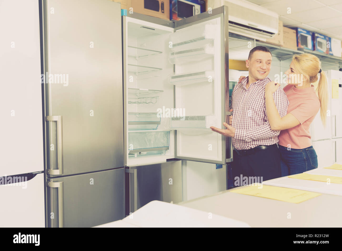Family couple selecting new fridge in household appliances store Stock ...