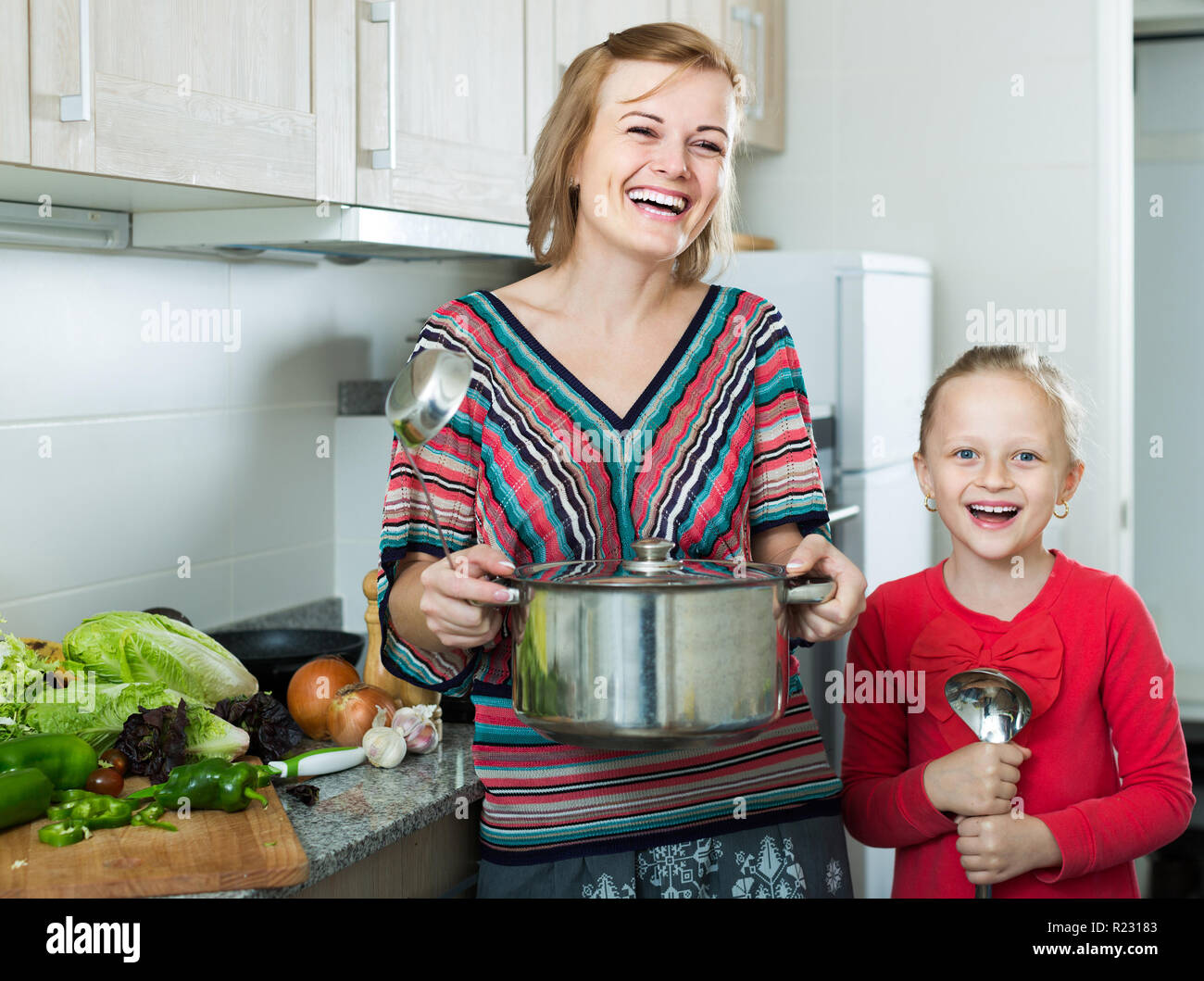 smiling mother and little daughter tasting soup together Stock Photo ...