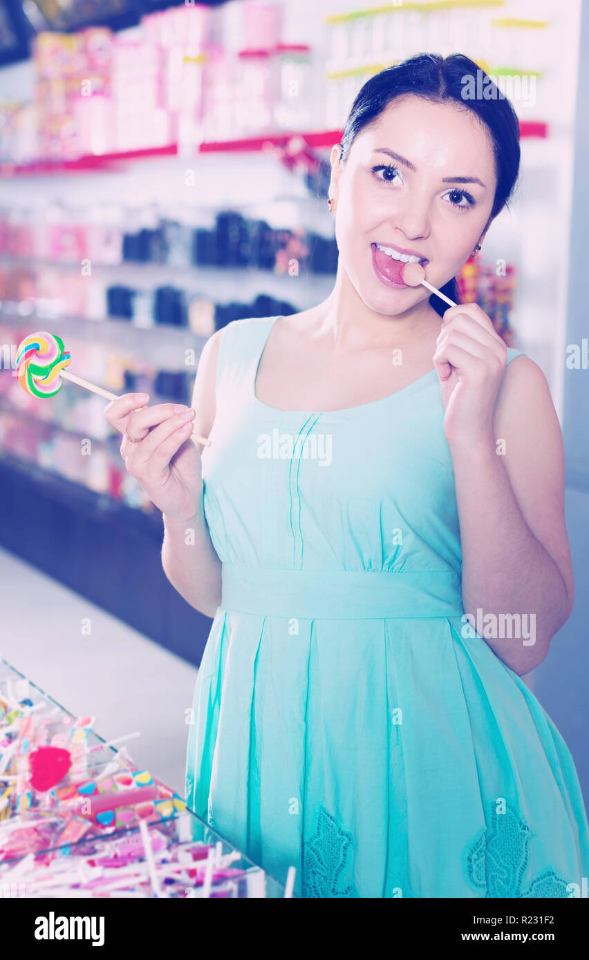 Positive girl in the shop taking candy in hands indoors Stock Photo - Alamy