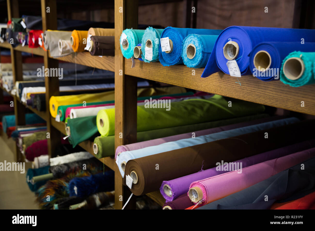 Variety of different fabric bolts exposed on shelves of fabric shop ...