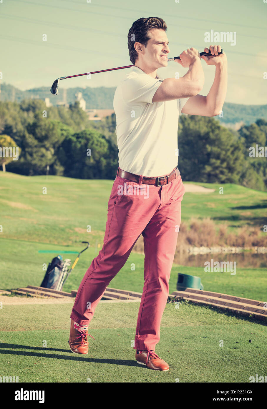Glad cheerful positive male golf player made successful hit at golf ...