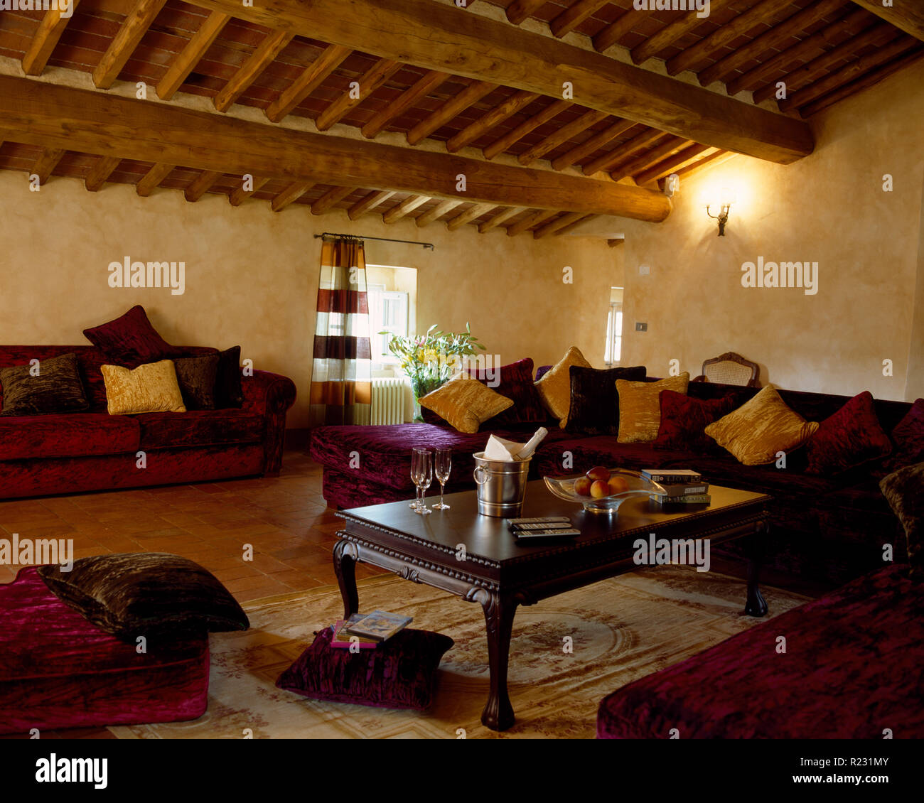 Rustic wooden beamed ceiling in Italian sitting room with red sofas ...
