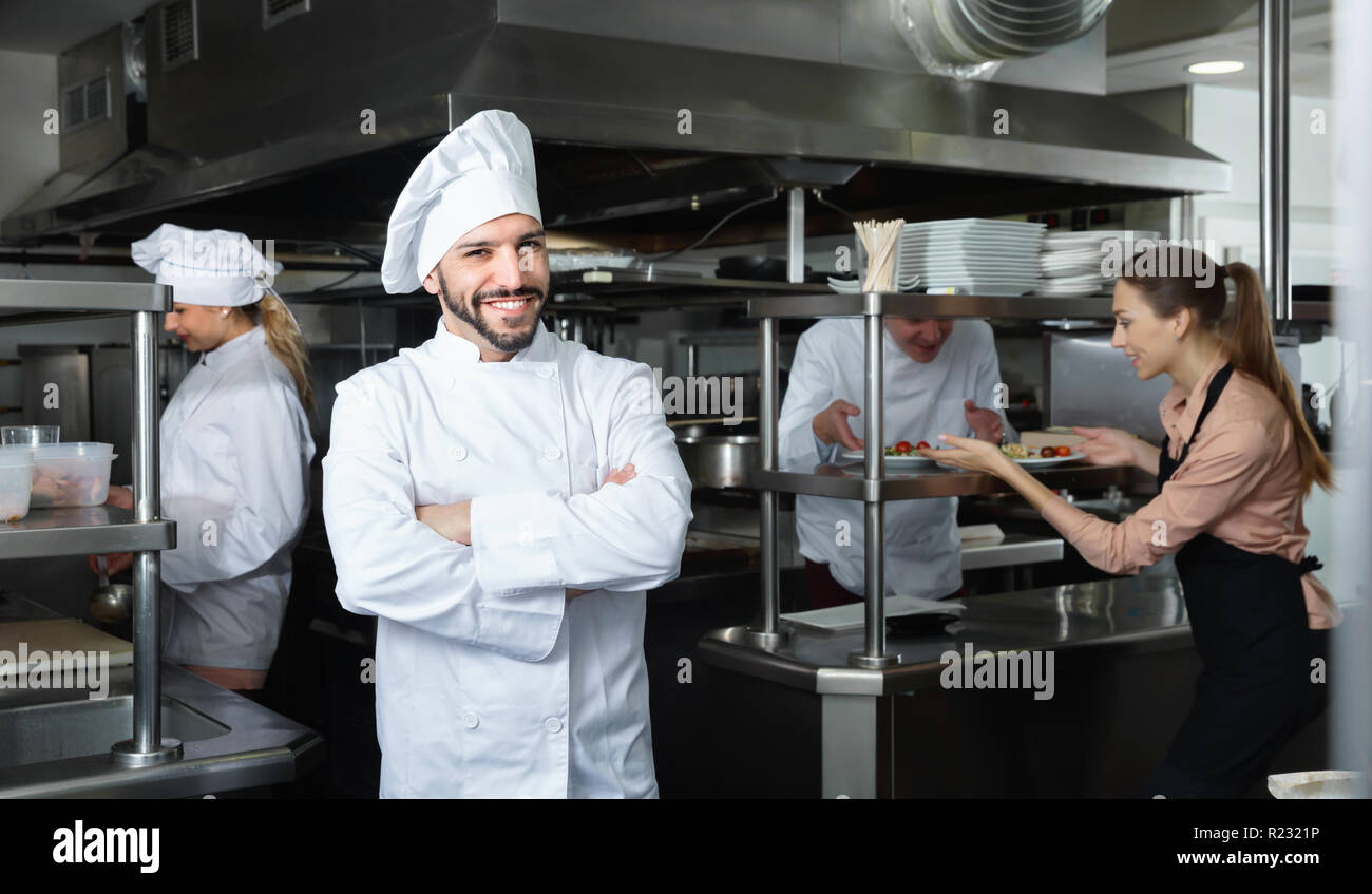 Portrait of cheerful positive smiling chef on restaurant kitchen with ...