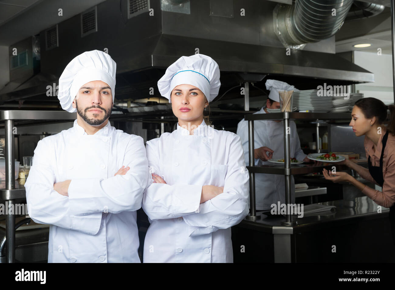 Portrait of two confident chefs posing with crossed arms in ...