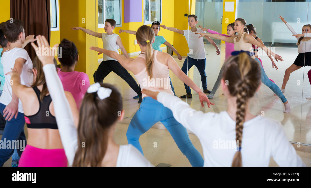 Rear view of group of teenagers exercising with female coach in front ...