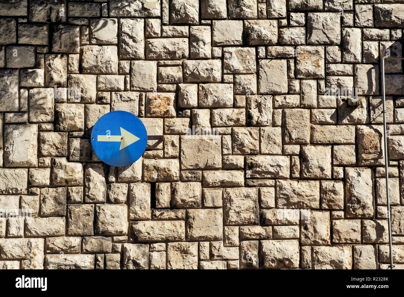 Traffic sign one way street sign with an arrow on a stone wall is a ...
