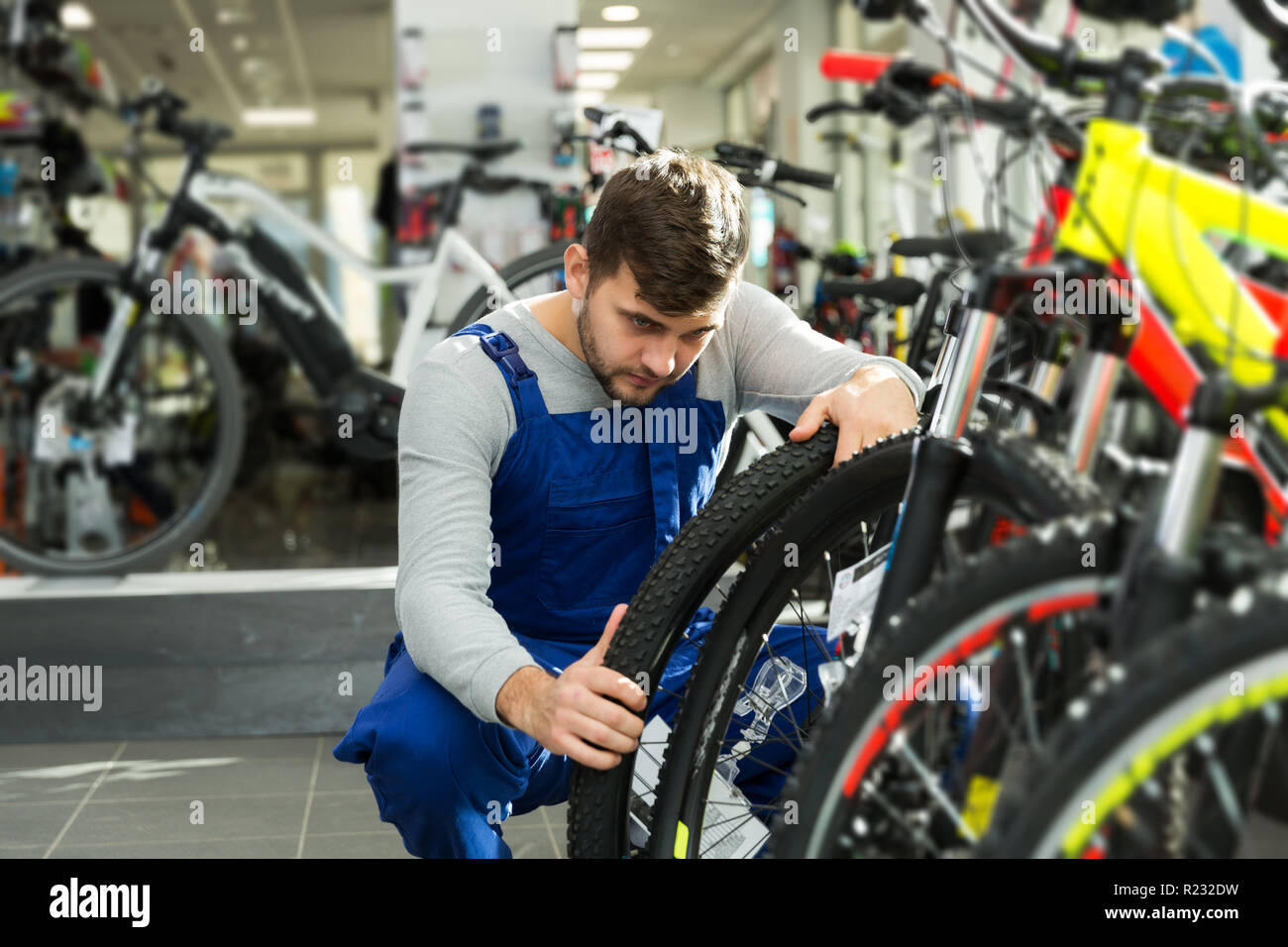 Portrait of professional man checking tire on wheel in bicycle shop ...