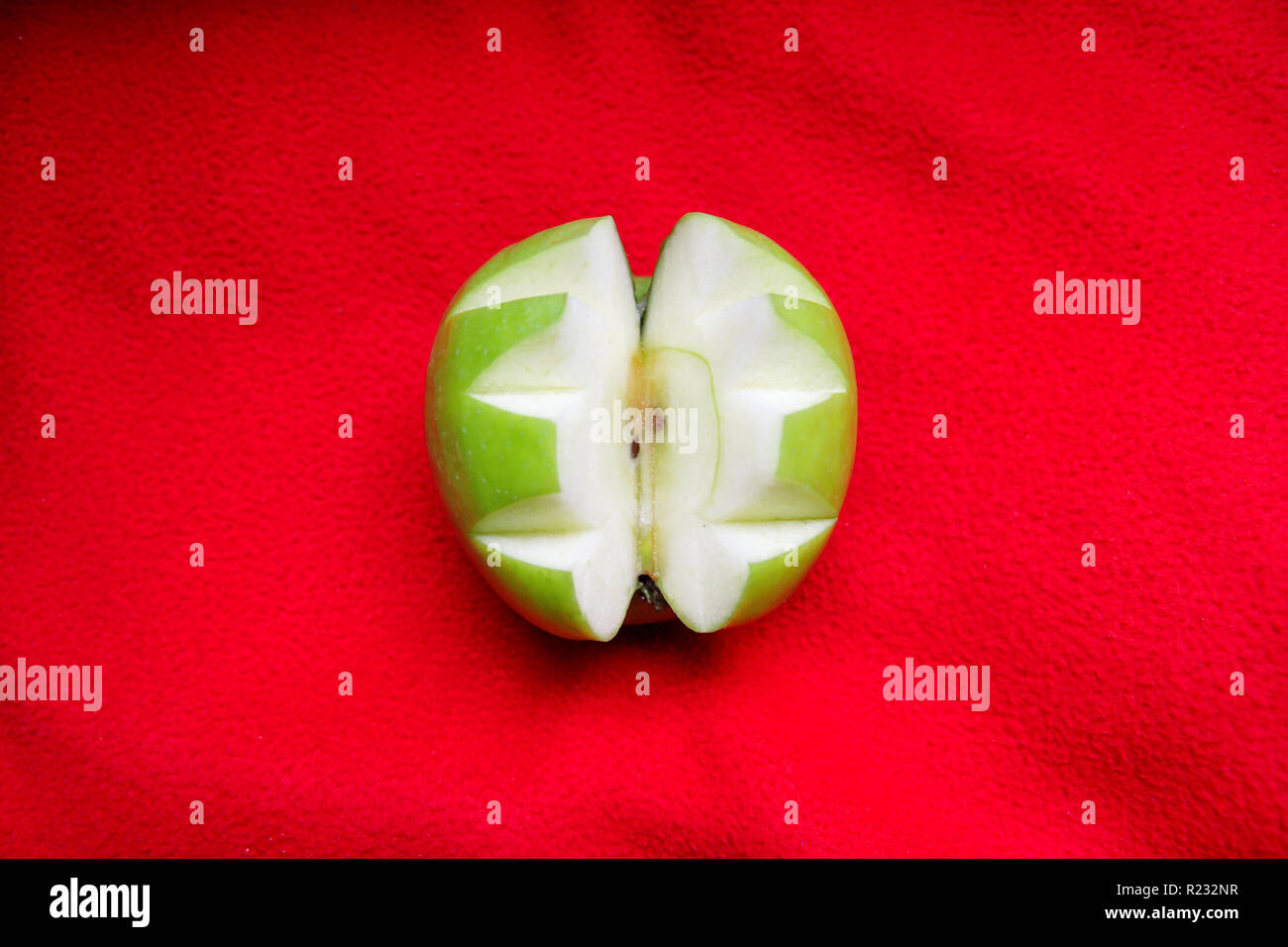 Carved apple isolated on red background, close up / Green apple cut out ...