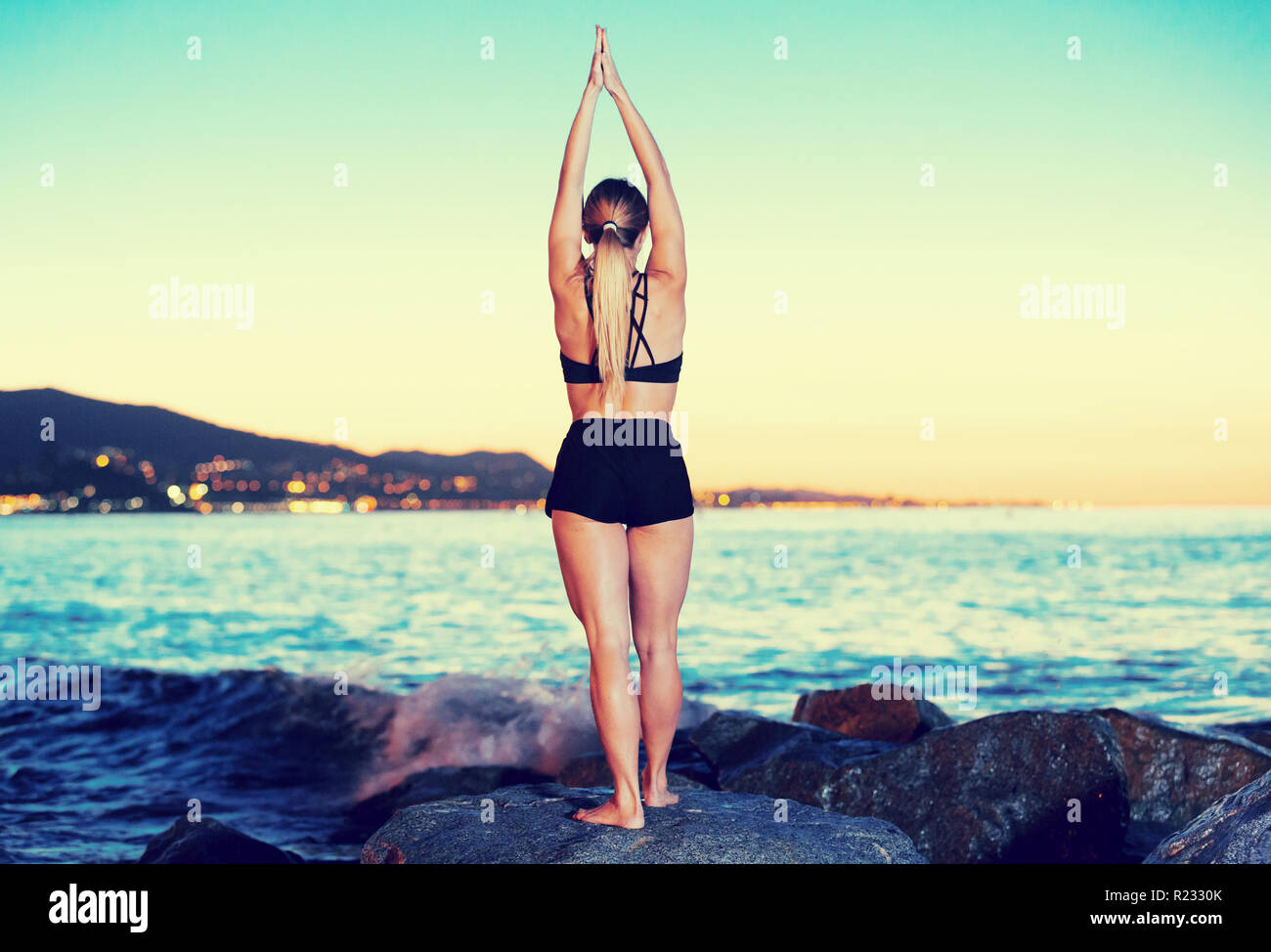 Female 24-31 years old is practicing stretching on a rock near sea at ...