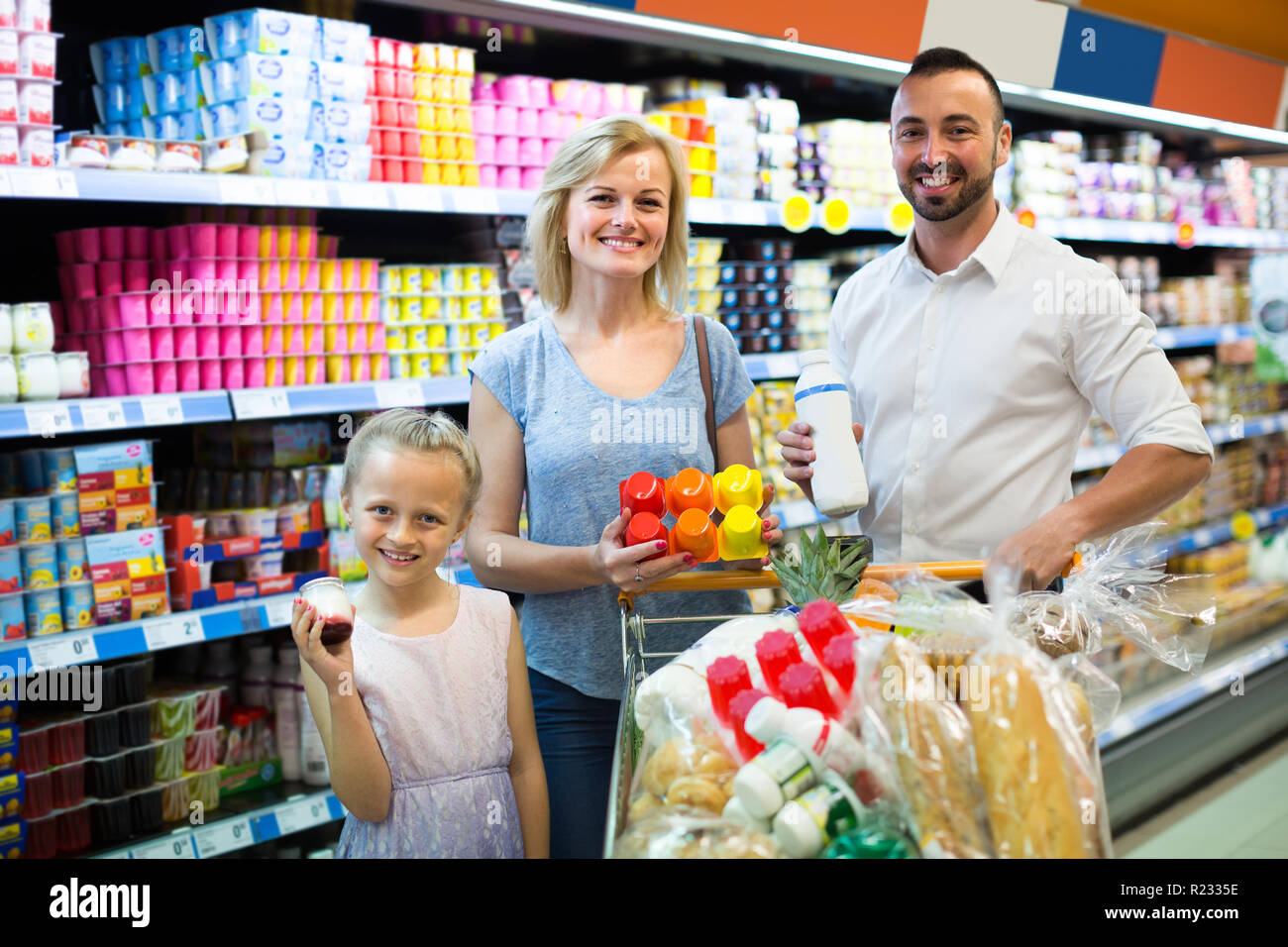 Happy smiling family shopping various dairy products in supermarket ...