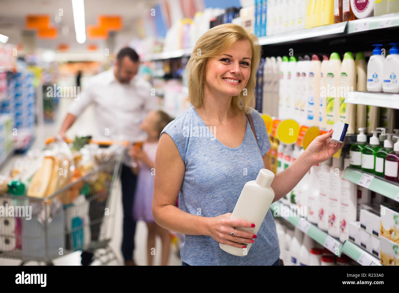 Smiling young female customer selecting haircare products in ...