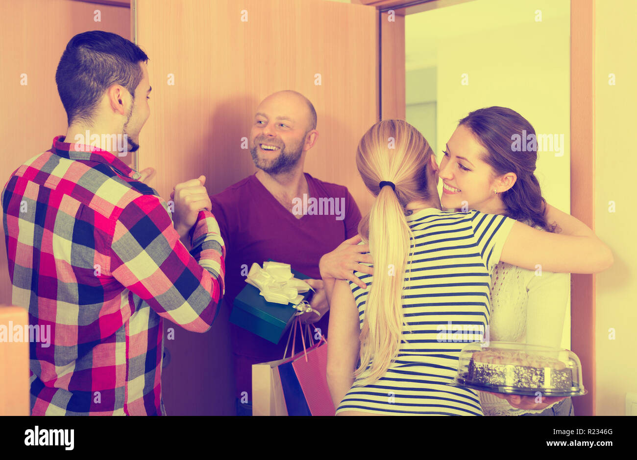 Happy smiling guests with presents and cake standing in doorway. Focus ...