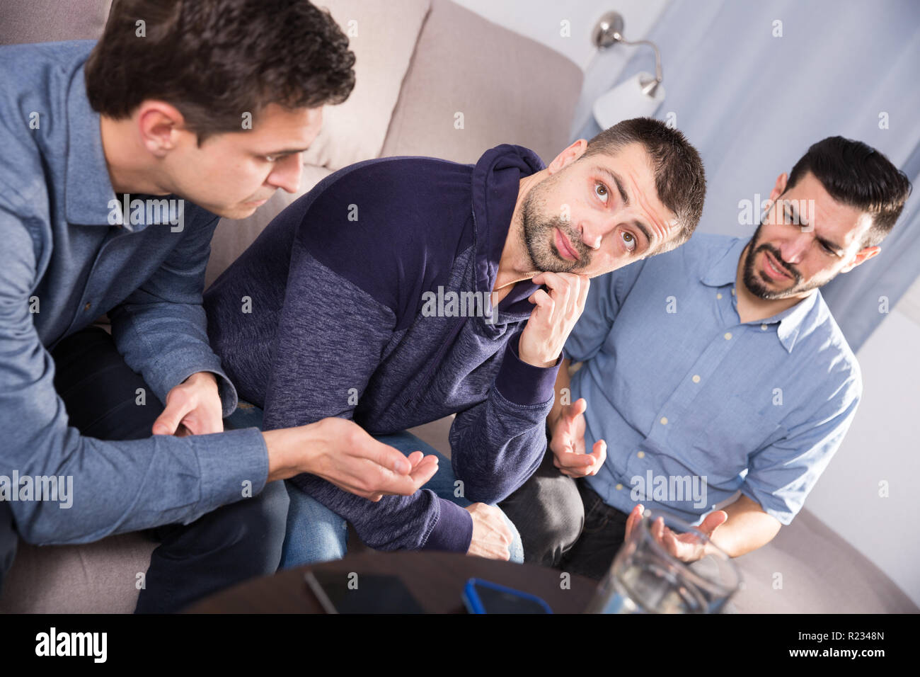 Two troubled men having serious talk with their friend at home Stock ...