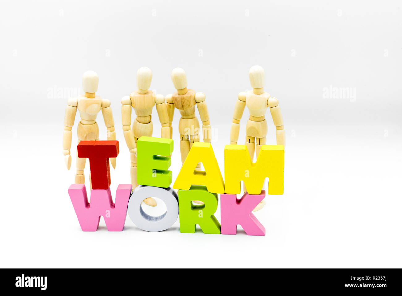 Wooden figures posing as business men behind the word TEAMWORK ...