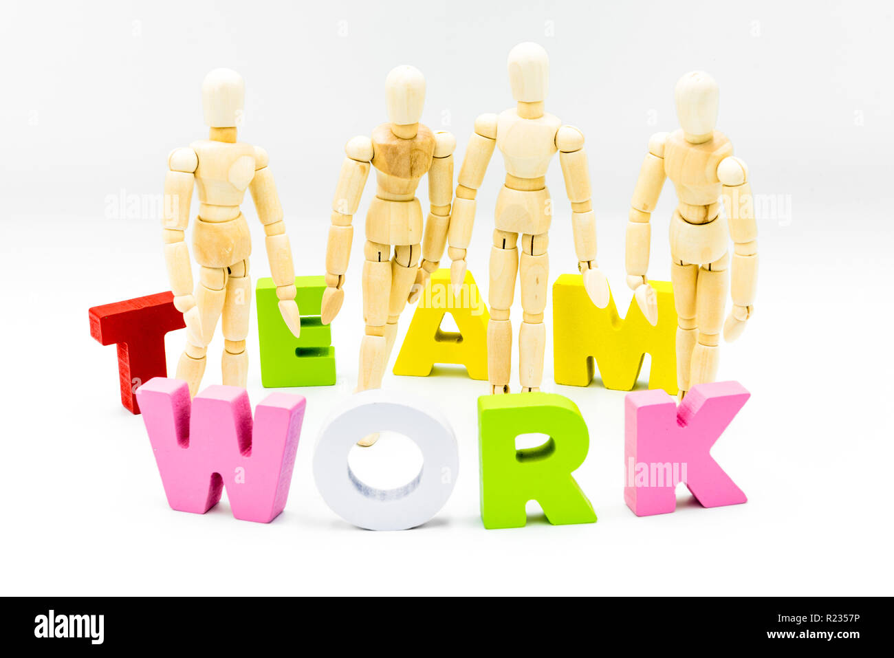 Wooden figures posing as business men between the words TEAM and WORK ...