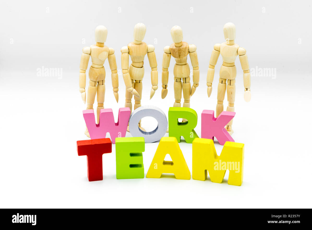 Wooden figures posing as business men behind the words TEAM and WORK ...